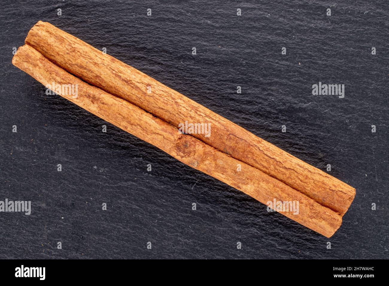 One stick of fragrant cinnamon on a slate stone, close-up, top view ...