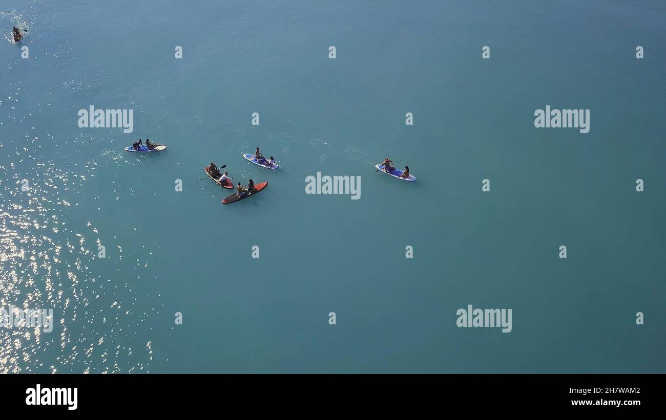 Tourists floating on SUP Board in blue sea. Clip. Top view of group of ...