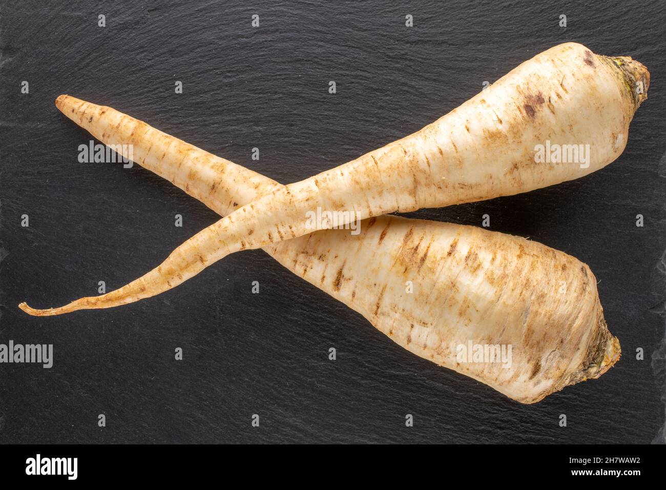 Two fragrant parsnip roots on a slate stone, close-up, top view Stock ...