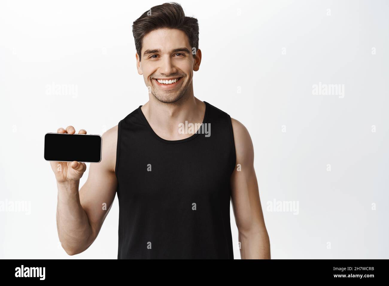 Handsome fit guy showing horizontal smartphone screen, demonstrating ...
