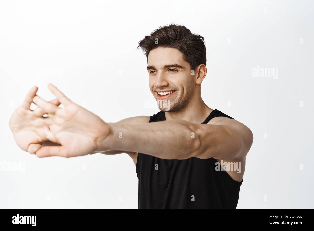 Smiling fit guy, athletic man doing sport workout, stretching arms and ...