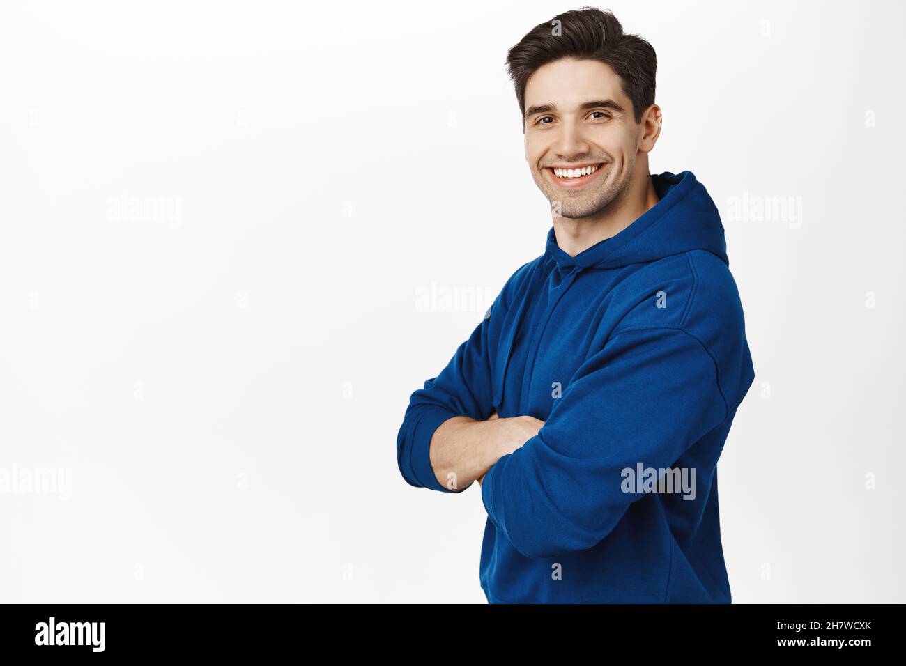Portrait of smiling confident young man cross arms on chest, standing ...