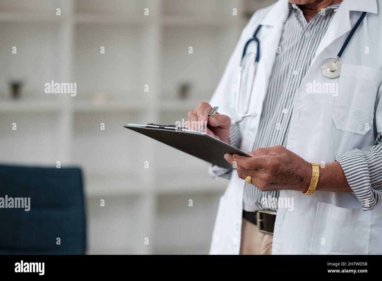 Cropped shot of doctor in uniform with stethoscope taking note patient ...