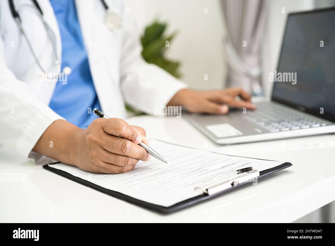 Doctor write health medical note in clipboard with laptop in hospital ...