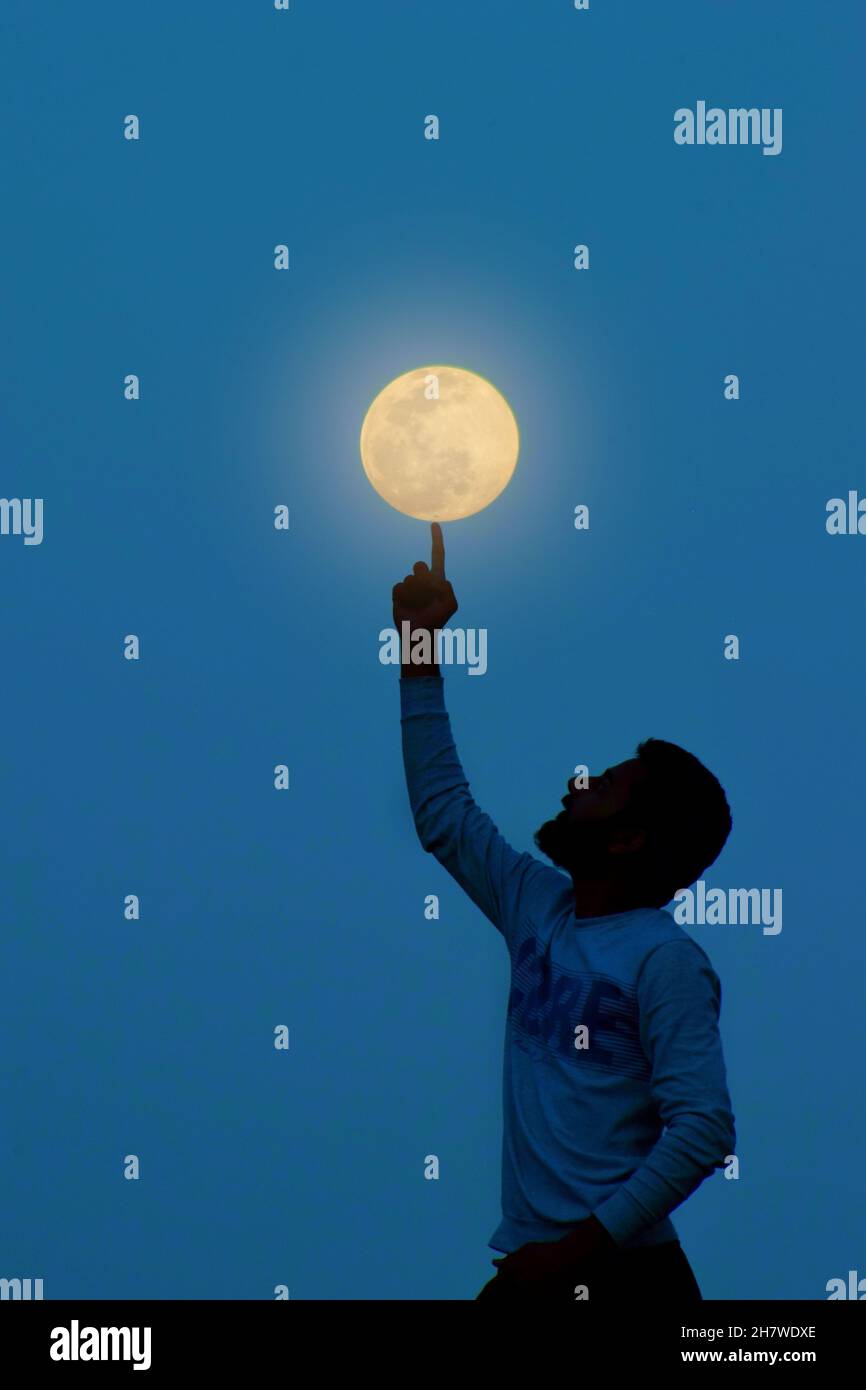 A man holding up the moon with his finger. HARYANA, INDIA: TRICK-of-the ...
