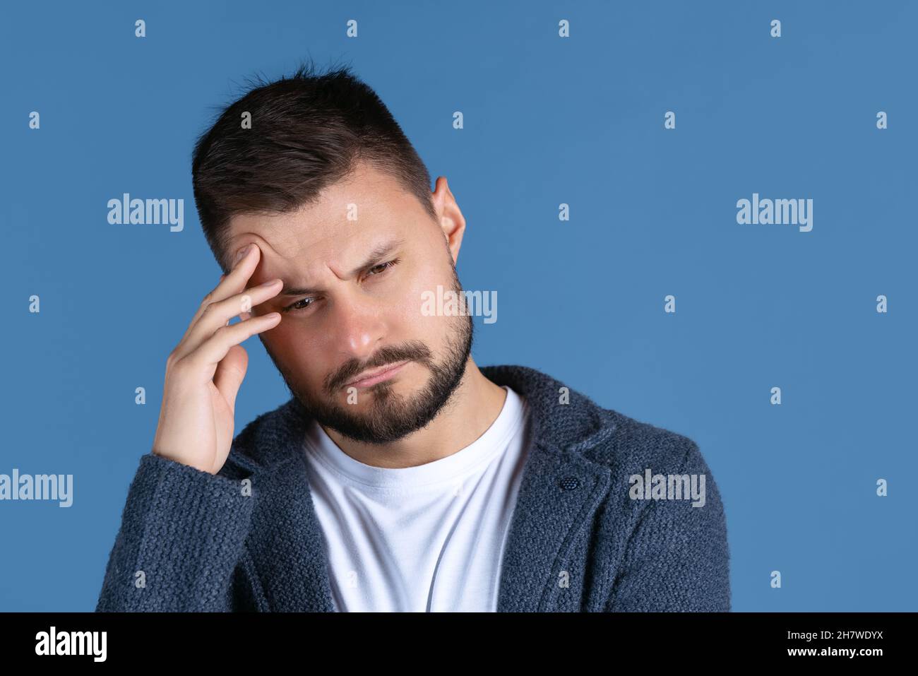 Cropped portrait of seriously looking, tired man touching head ...