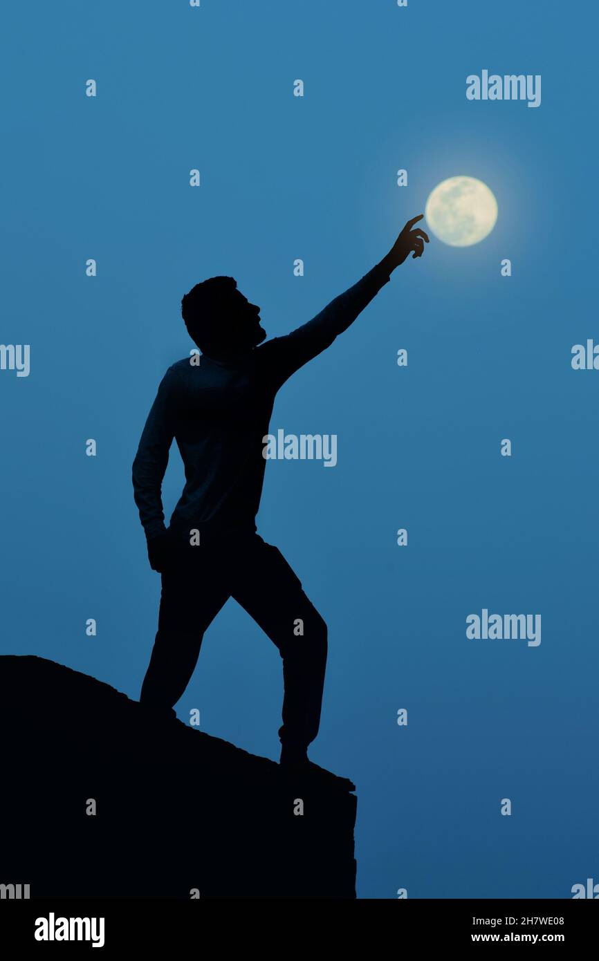 A man reaching out to grab the moon. HARYANA, INDIA: TRICK-of-the-eye ...