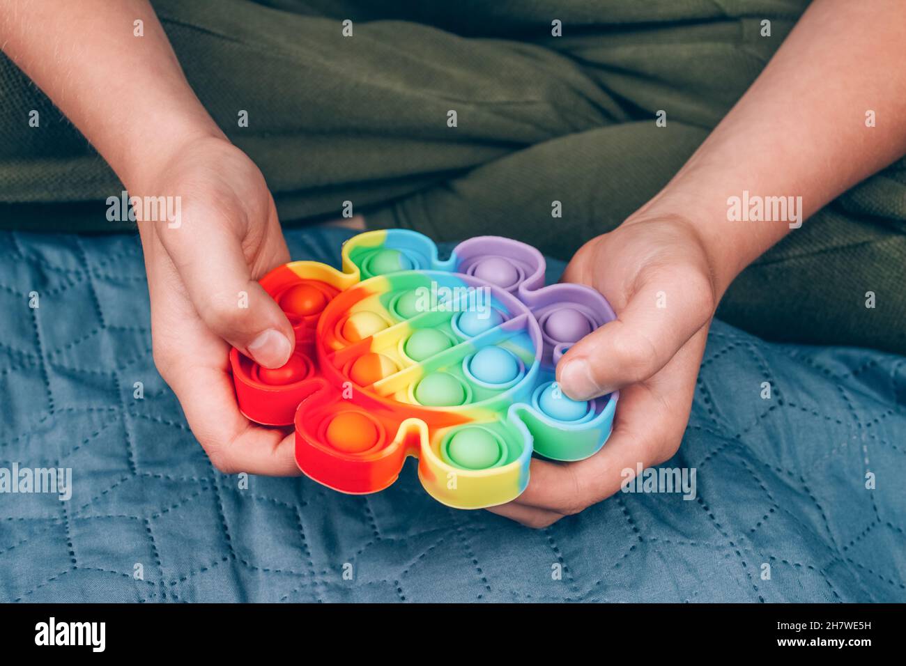 Boy's hands playing with rainbow pop it fidget toy. Push bubble fidget ...