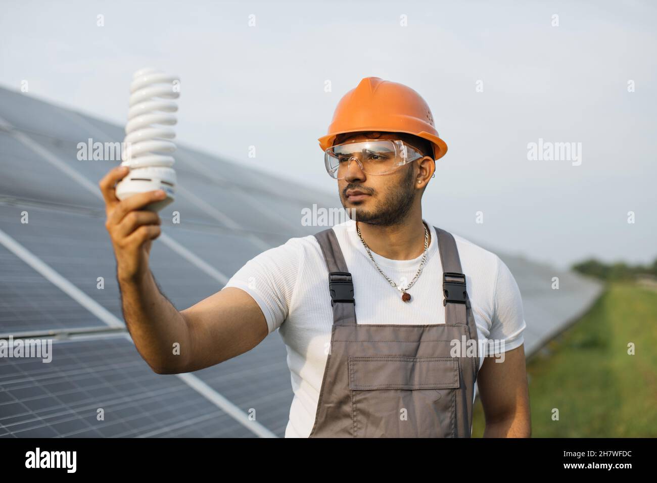 Male arab engineer holding low energy light bulb while standing on ...