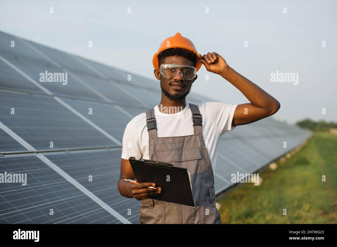 Competent technician with clipboard doing inspection of solar panels ...