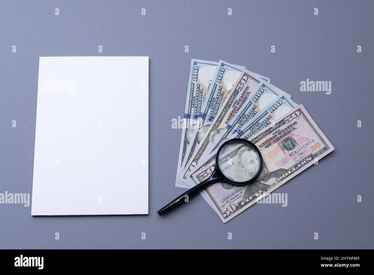 American banknotes under a magnifying glass on a gray background with a ...