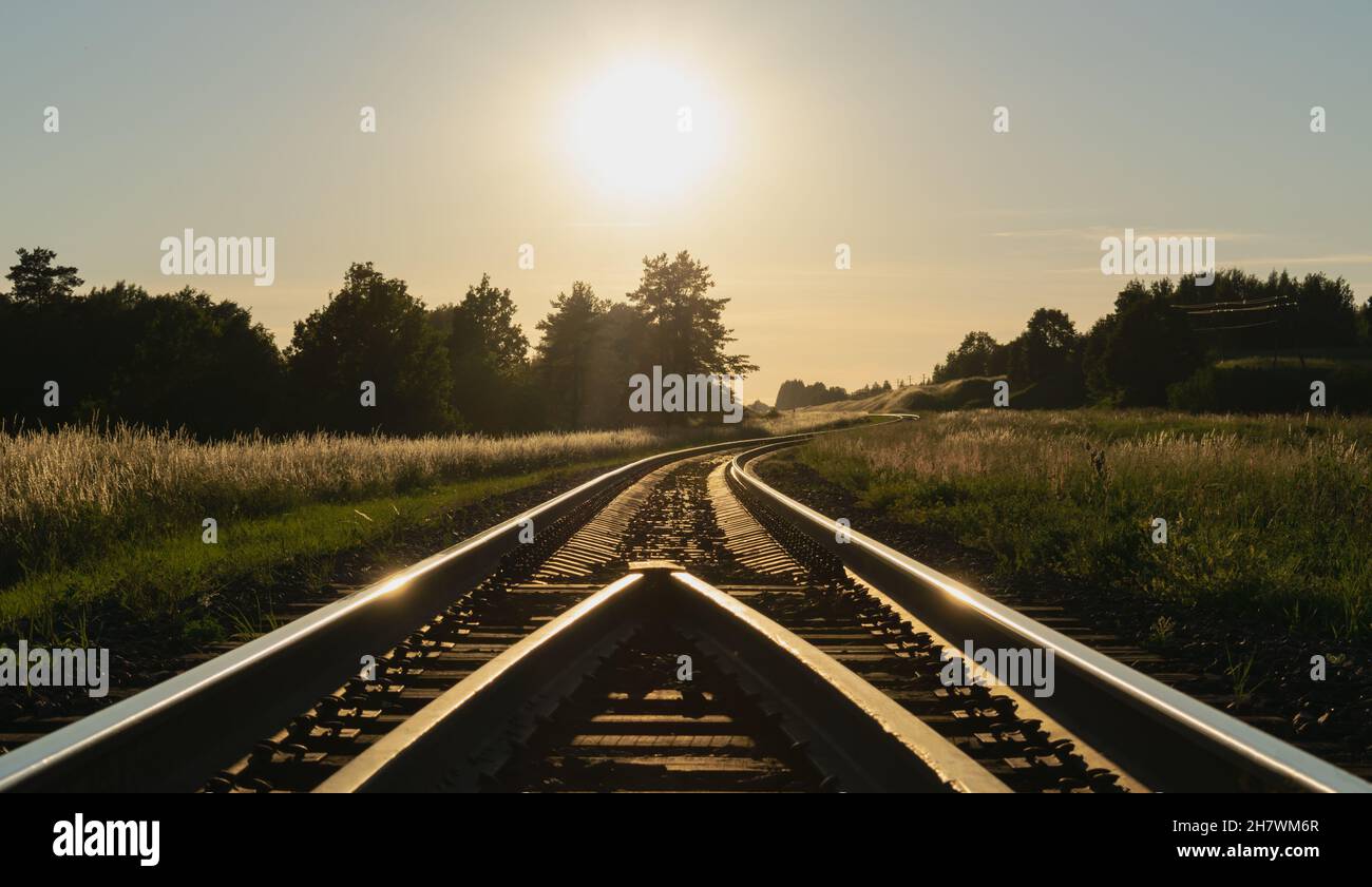 A beautiful summer sunset over the empty railroad tracks running ...