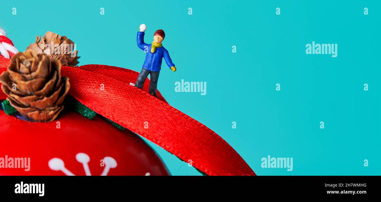 a miniature boy throw a snowball standing on a red christmas ornament ...