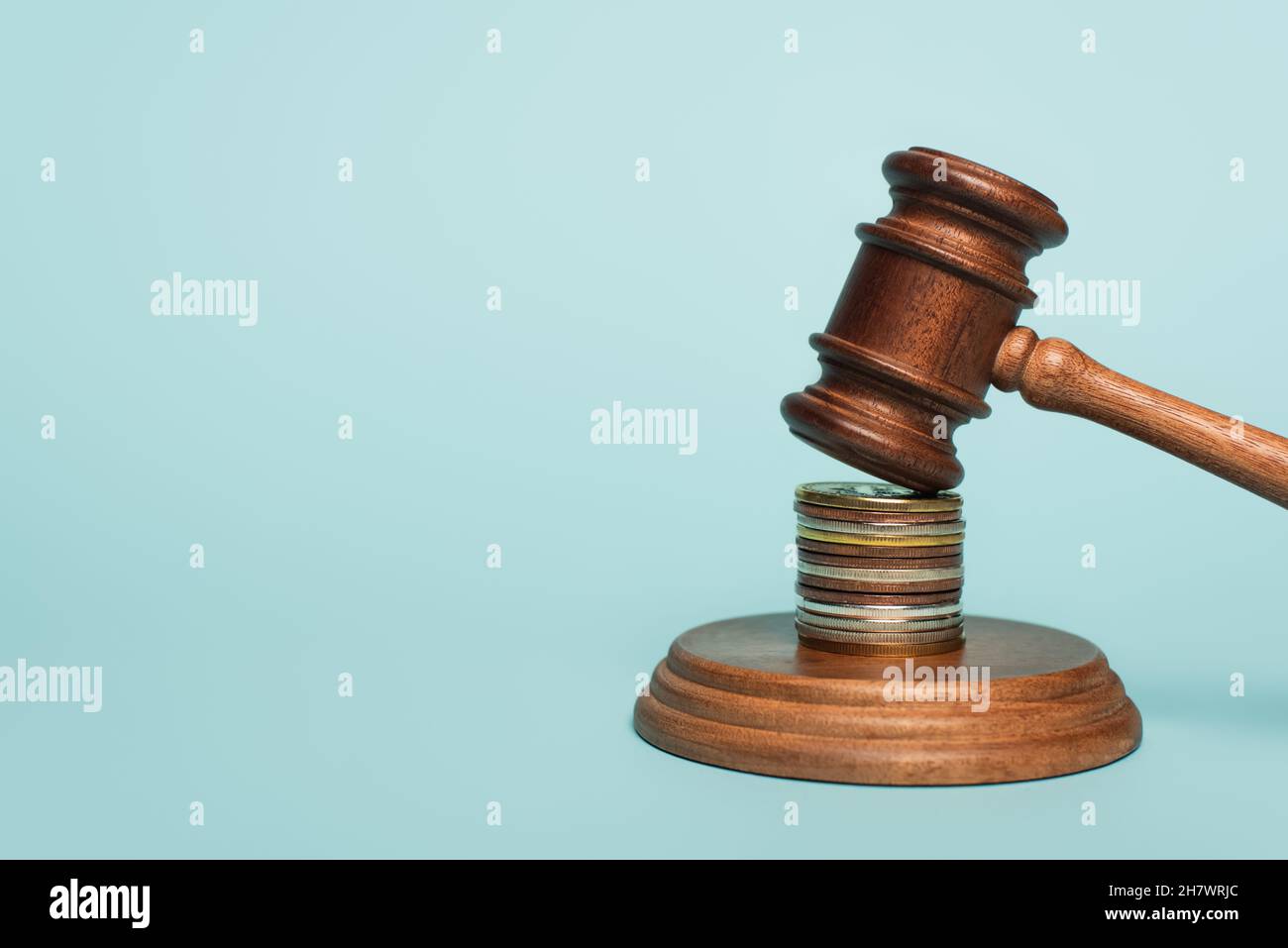 wooden gavel on stacked golden and silver coins on blue, anti ...