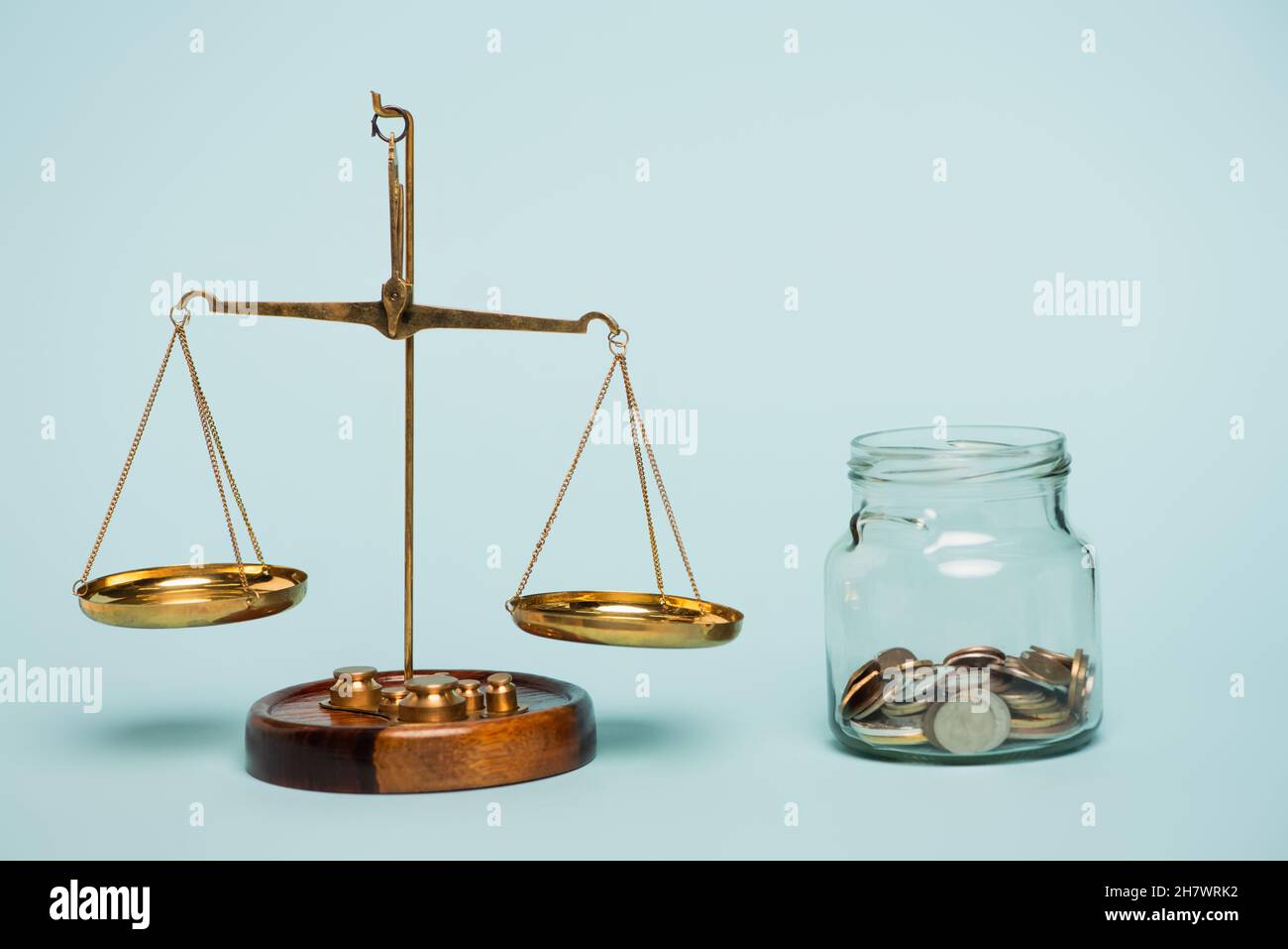 bronze justice scales near glass jar with coins on blue background ...