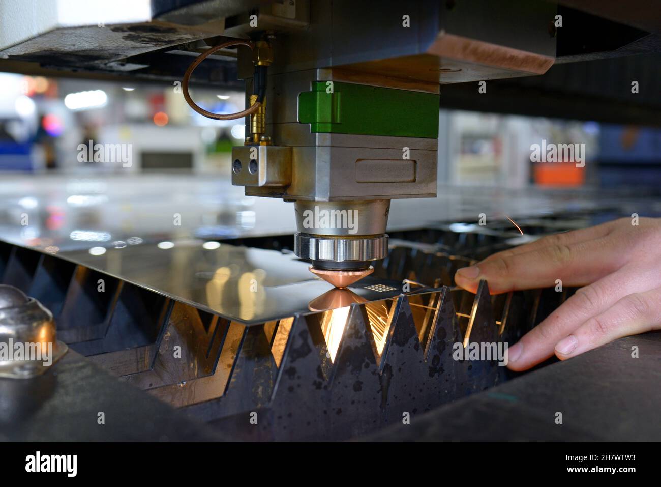 Laser machine cutting metal sheet, worker hand taking control, sparks ...