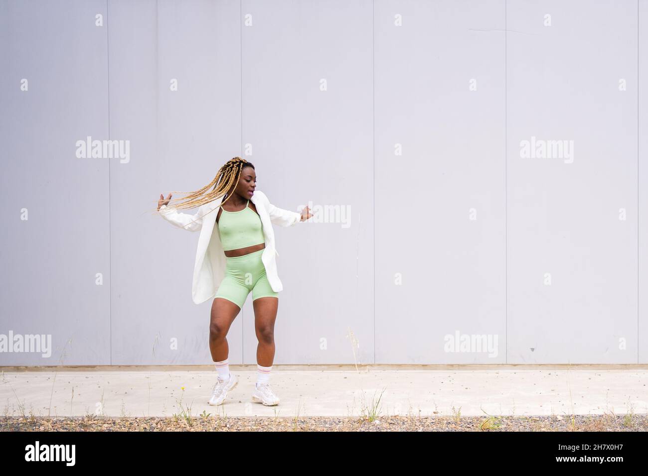 African fit woman dancing in front of an urban wall with sportive ...