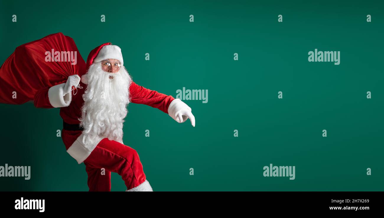 Surprised Santa Claus sneaking while carrying huge red sack with ...