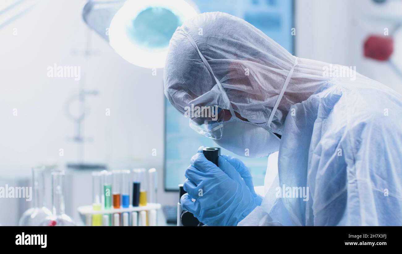 Researcher doctor with ppe equipment looking into medical microscope ...