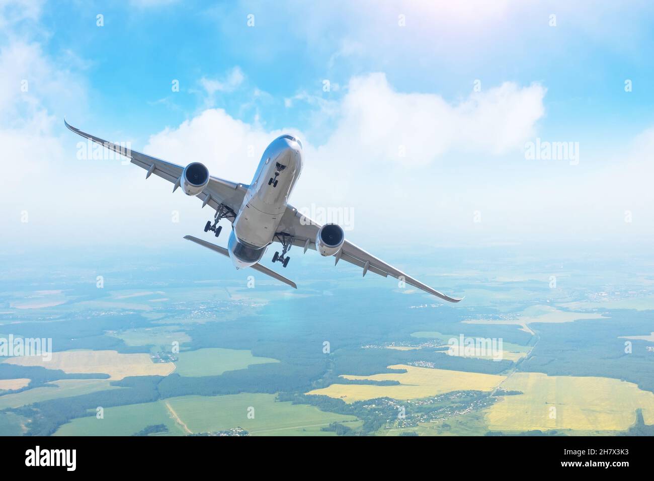 Flying passenger jet plane over fields and forests Stock Photo - Alamy