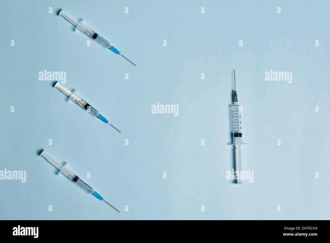 Syringes on bright blue background. Symbol of three Covid-19 booster ...