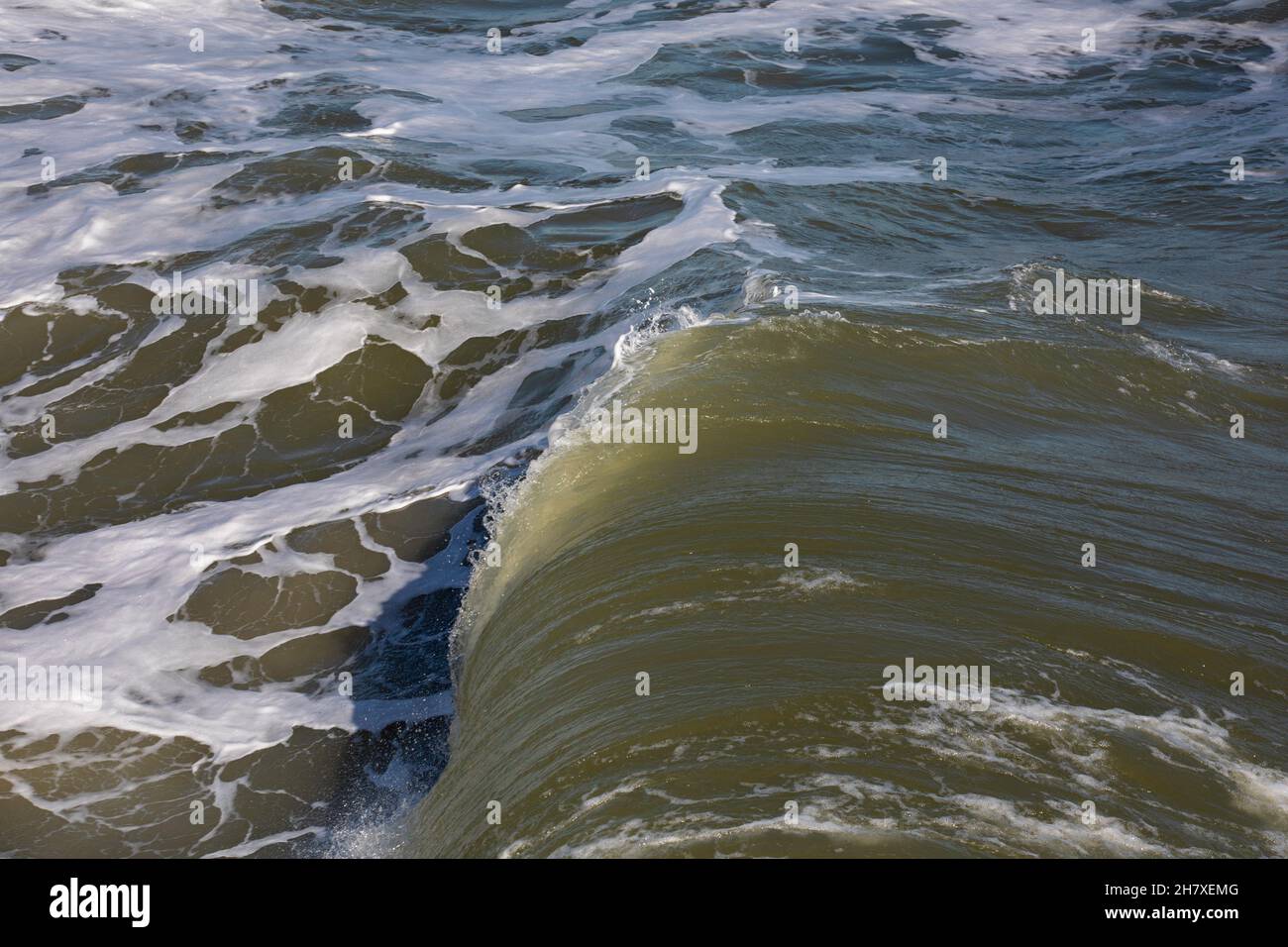 A single wave cresting during high tide and rough surf on the northeast ...