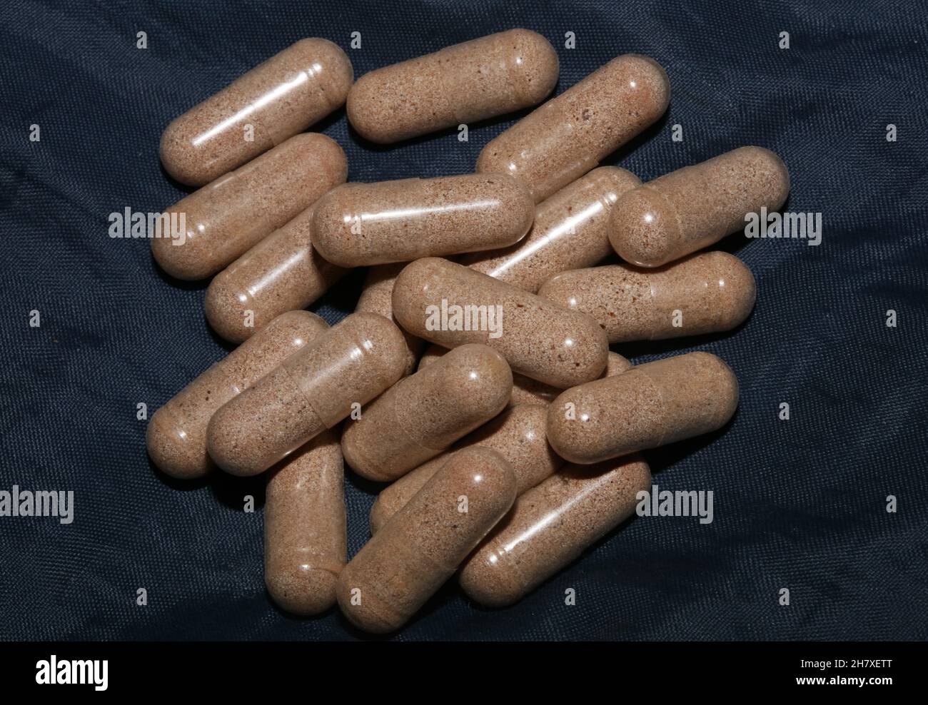 Transparent capsules filled with brown vitamins powder close up ...