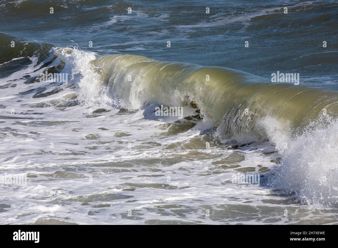 A single wave cresting during high tide and rough surf on the northeast ...