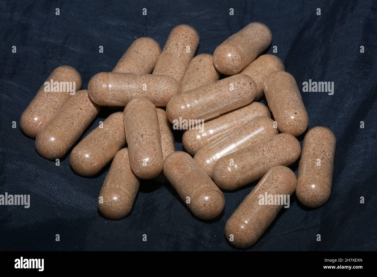 Transparent capsules filled with brown vitamins powder close up ...
