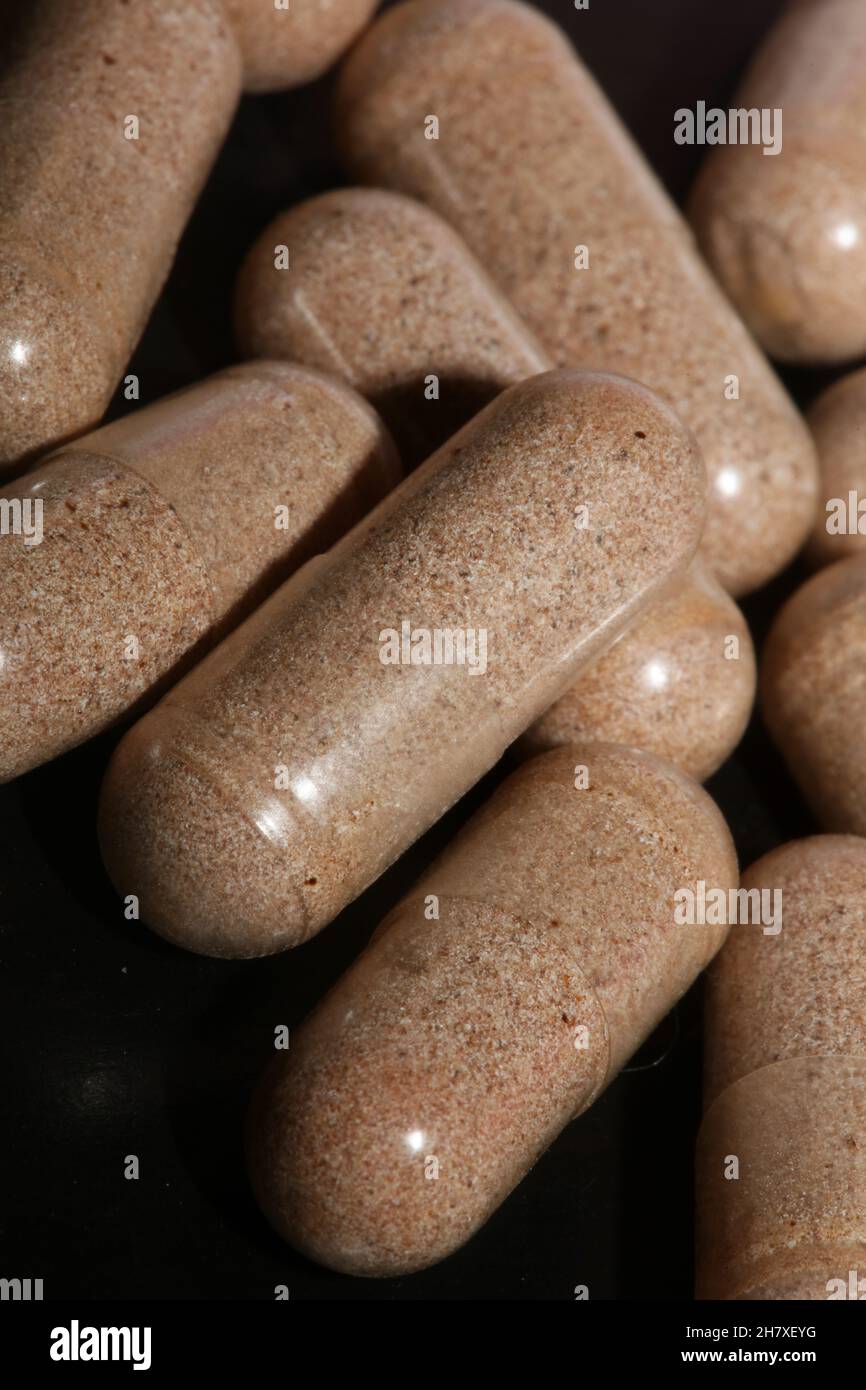 Transparent capsules filled with brown vitamins powder close up ...