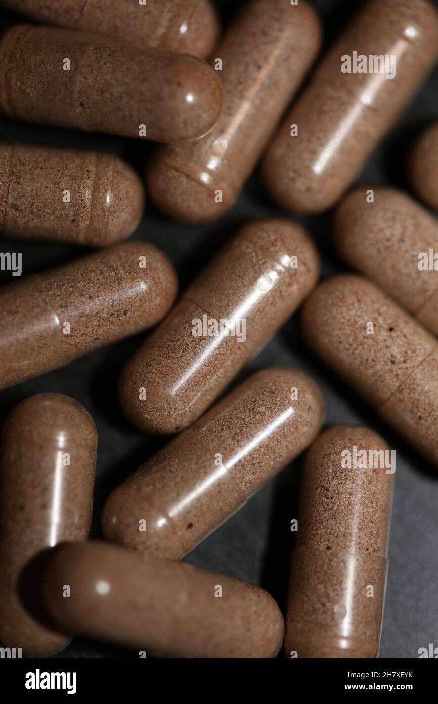 Transparent capsules filled with brown vitamins powder close up ...