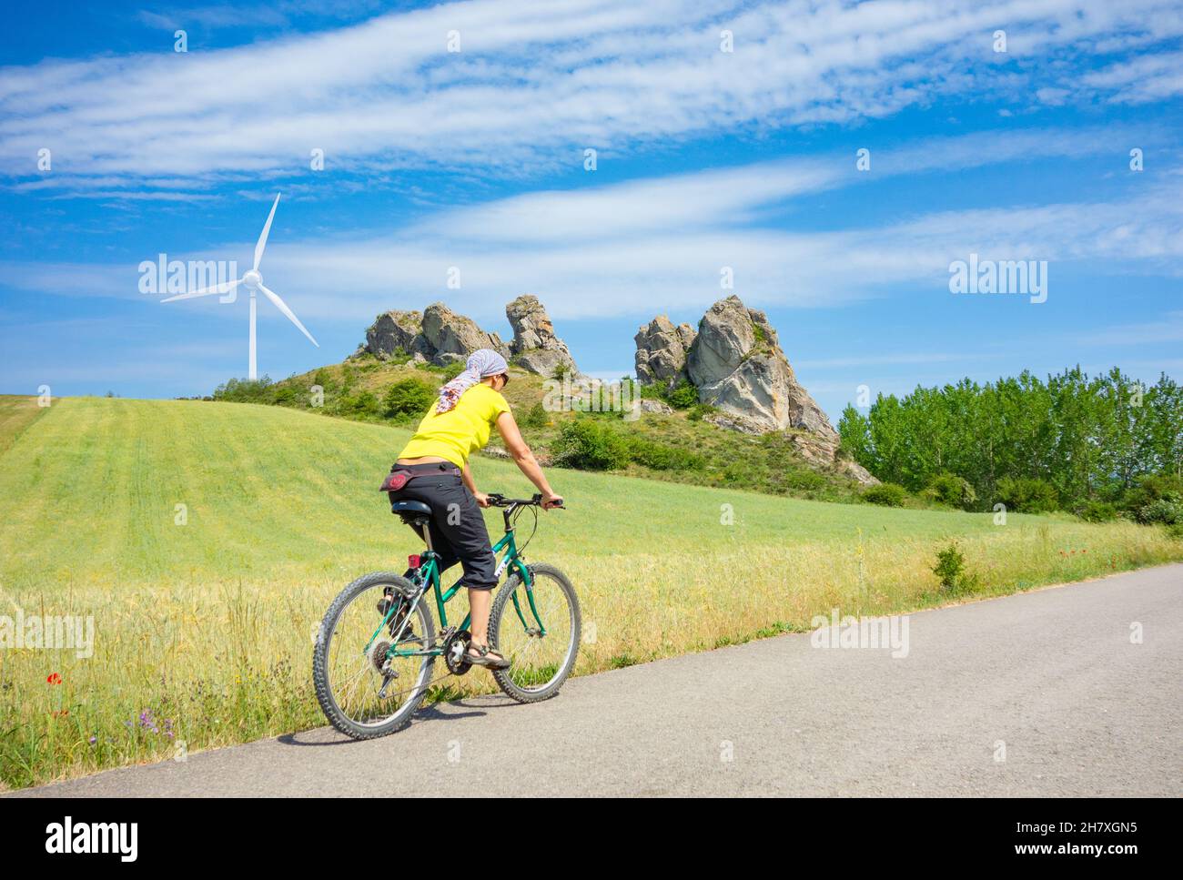 Woman riding bike, bicycle on country lane with wind turbine and blue ...