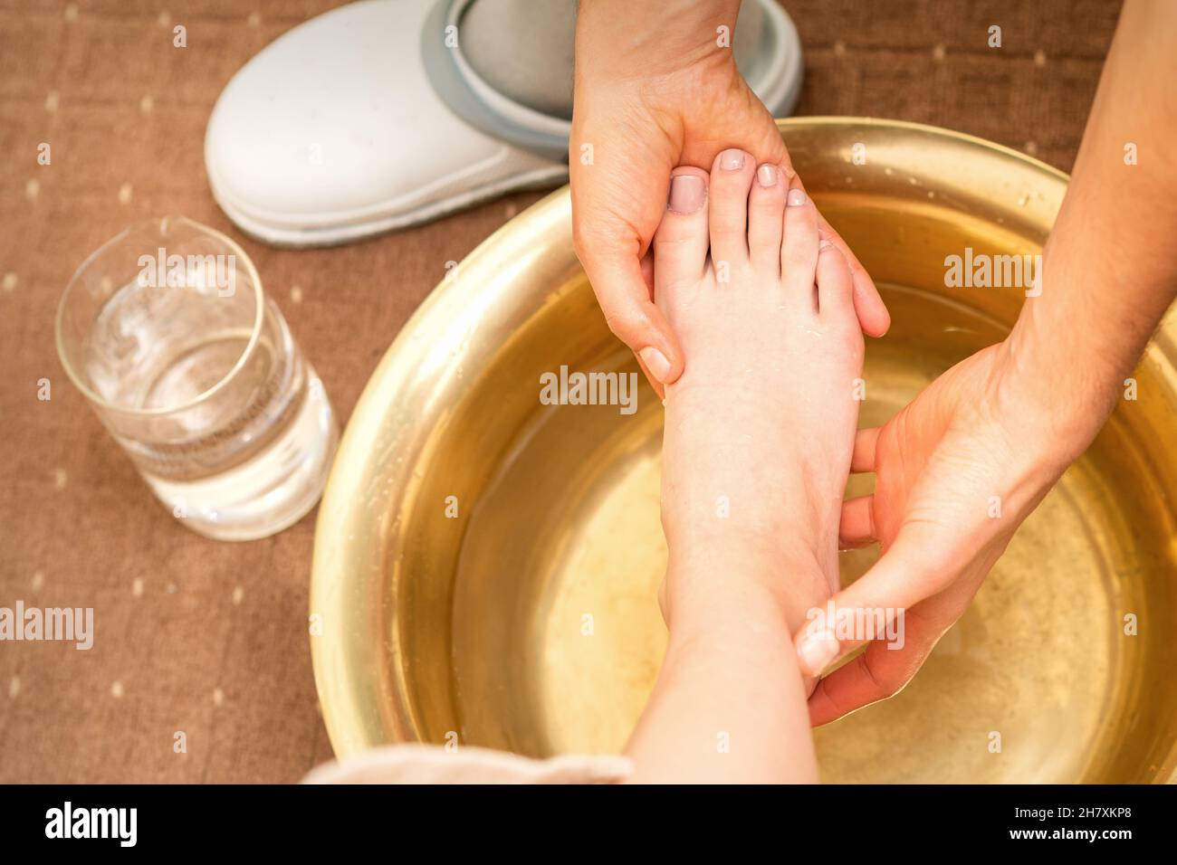 Washing female foot in a special container by male masseur in spa salon ...