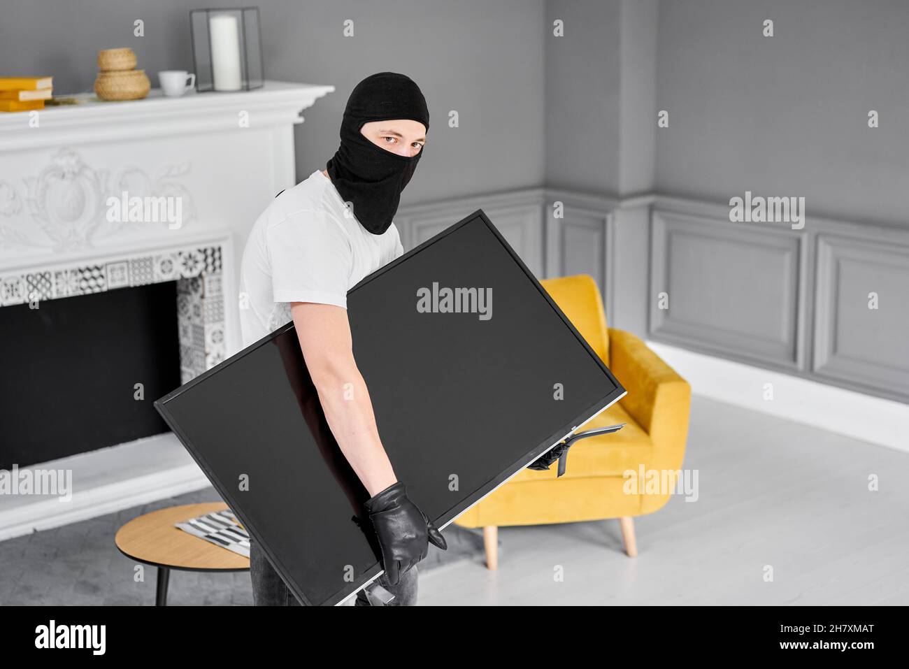 Thief with black balaclava stealing modern expensive television. Masked ...