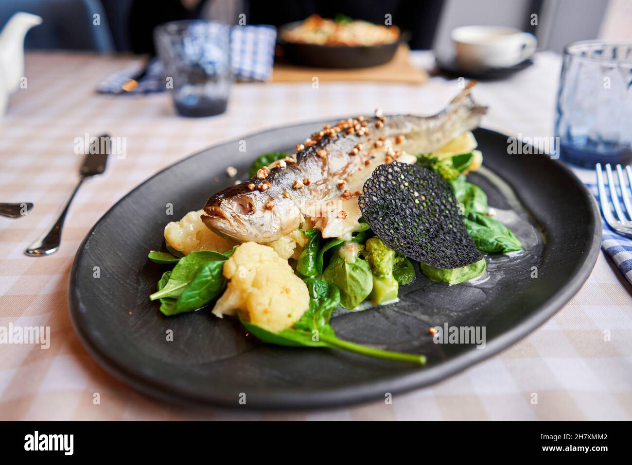 Roasted pike perch or cod fish with baked vegetables and spinach. Dish ...