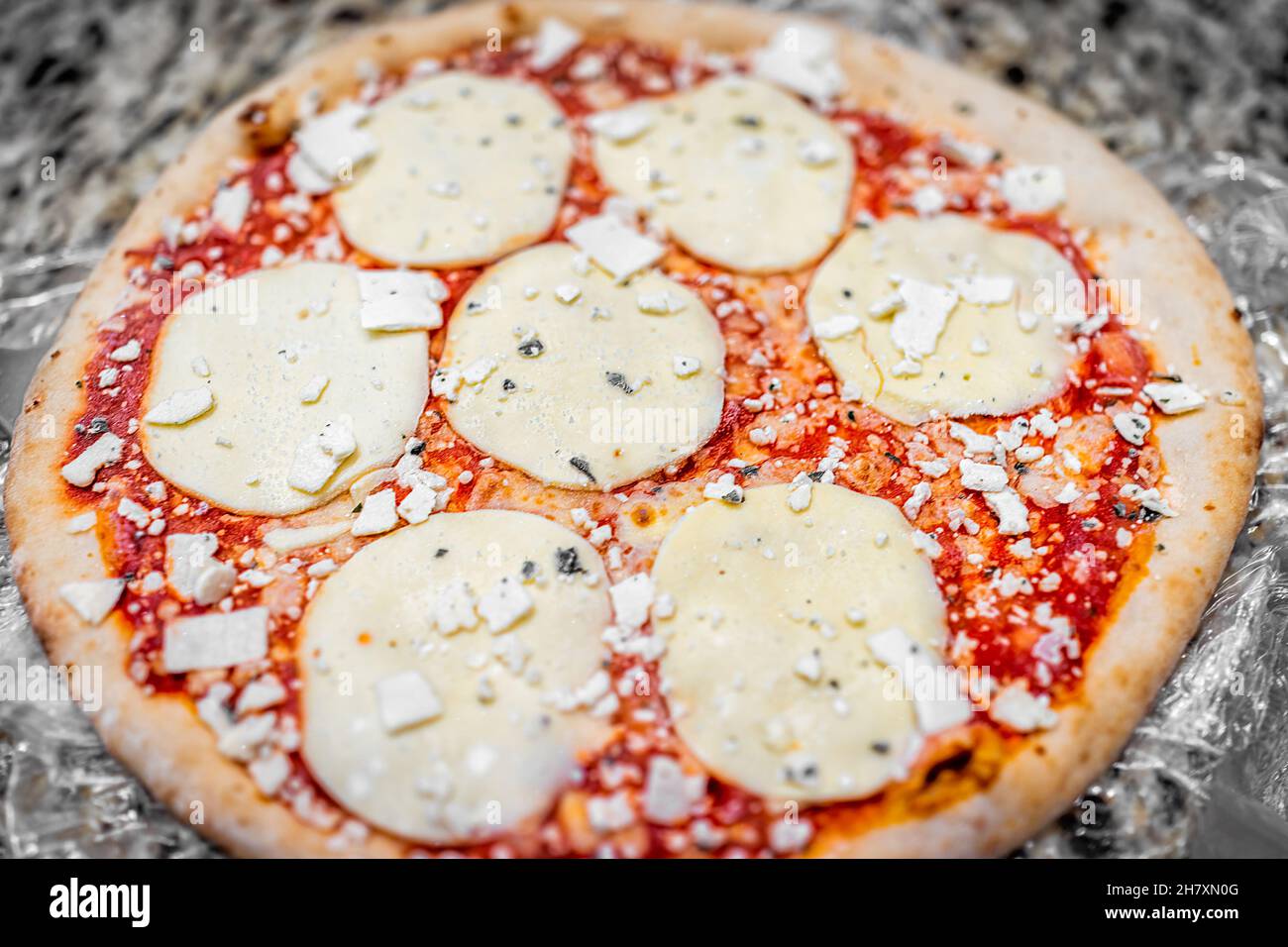Cooked frozen whole small pizza crust on table with melted mozzarella ...