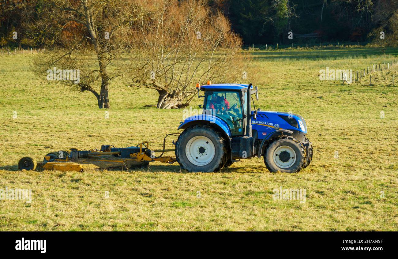 Large blue New Holland T7 210 tractor with a trailed grass topper Stock ...