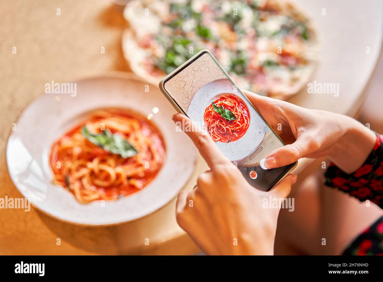 Woman with a mobile phone, takes a photo to for food blog and social ...
