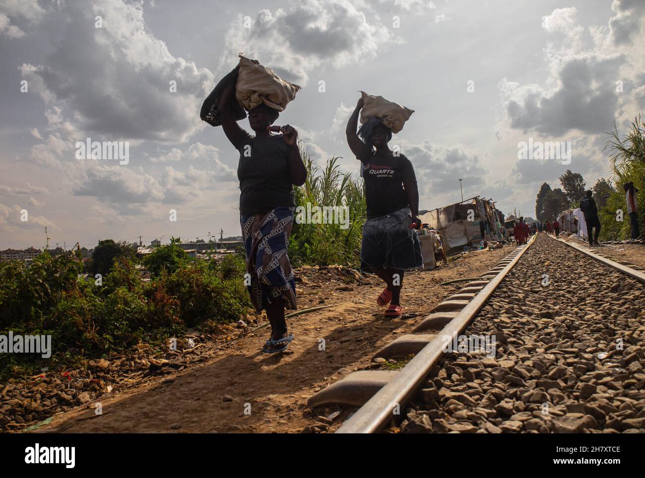 Women are seen walking along side the railway line carrying their ...