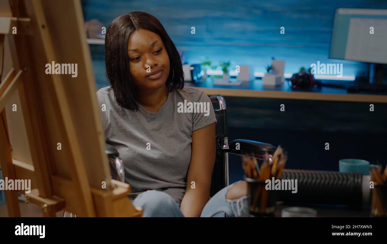 Portrait of black paralyzed artist drawing on canvas while sitting in ...