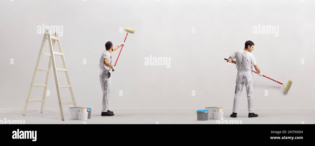 Rear view shot of house painters painting a wall isolated on white ...