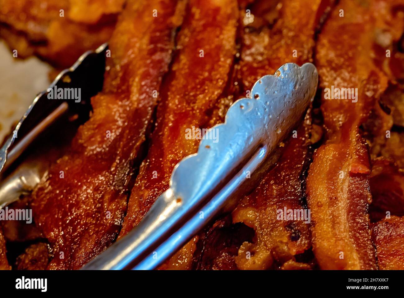 Strips of fried bacon lay in a pan with a pair of tongs, July 9, 2011 ...