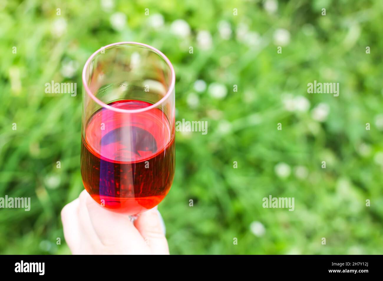 Glass with homemade red vine in a hand on farm yard background in a ...