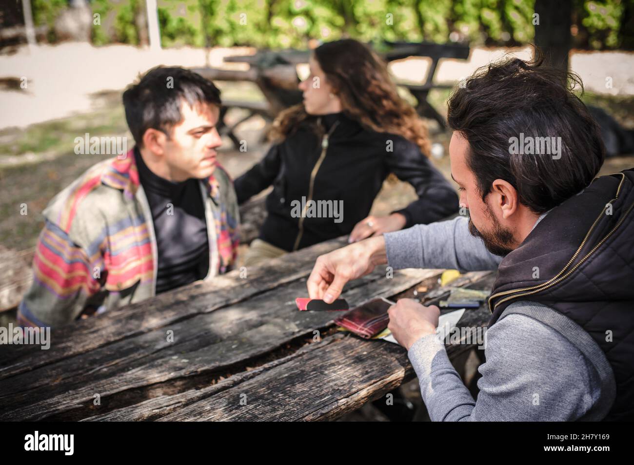 Group of friends preparing hashish joint rolling marijuana cigarette ...