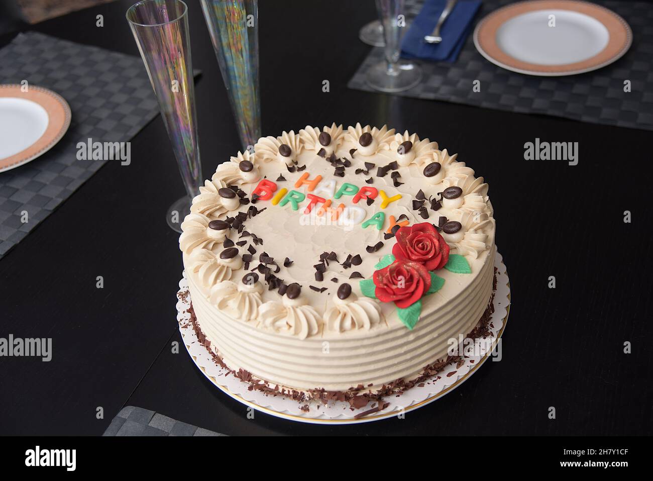 Decorated cream birthday cake in dining table setting Stock Photo - Alamy