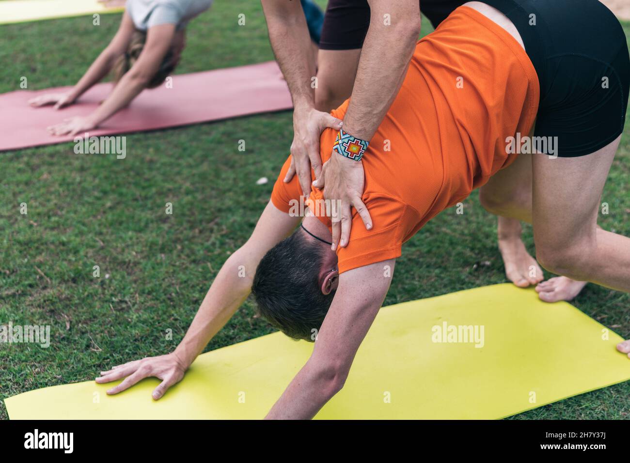 Coach correcting the yoga pose to a learner in an outdoor class Stock ...
