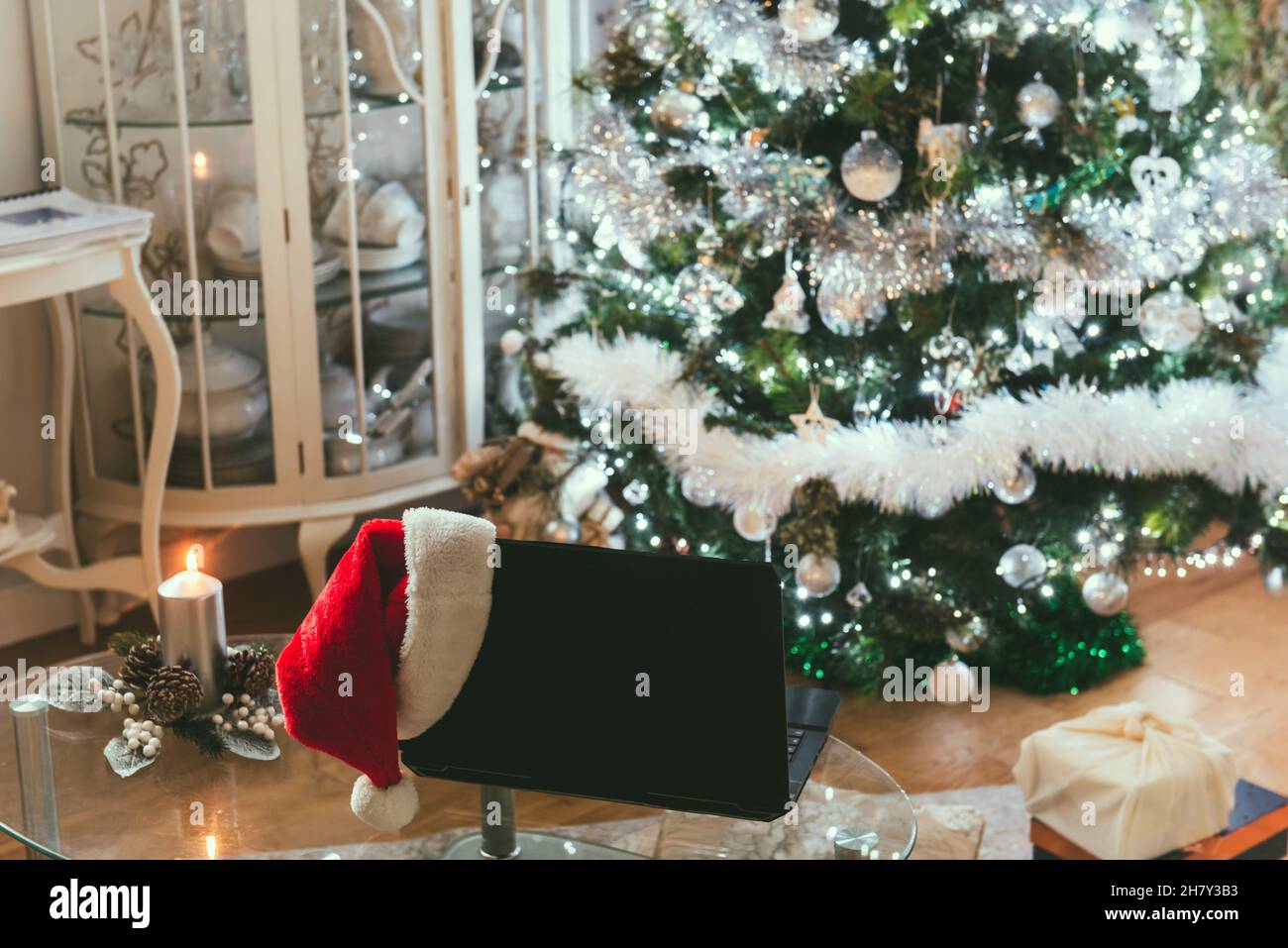 Laptop decorated with Santa hat on the background of festive Christmas ...