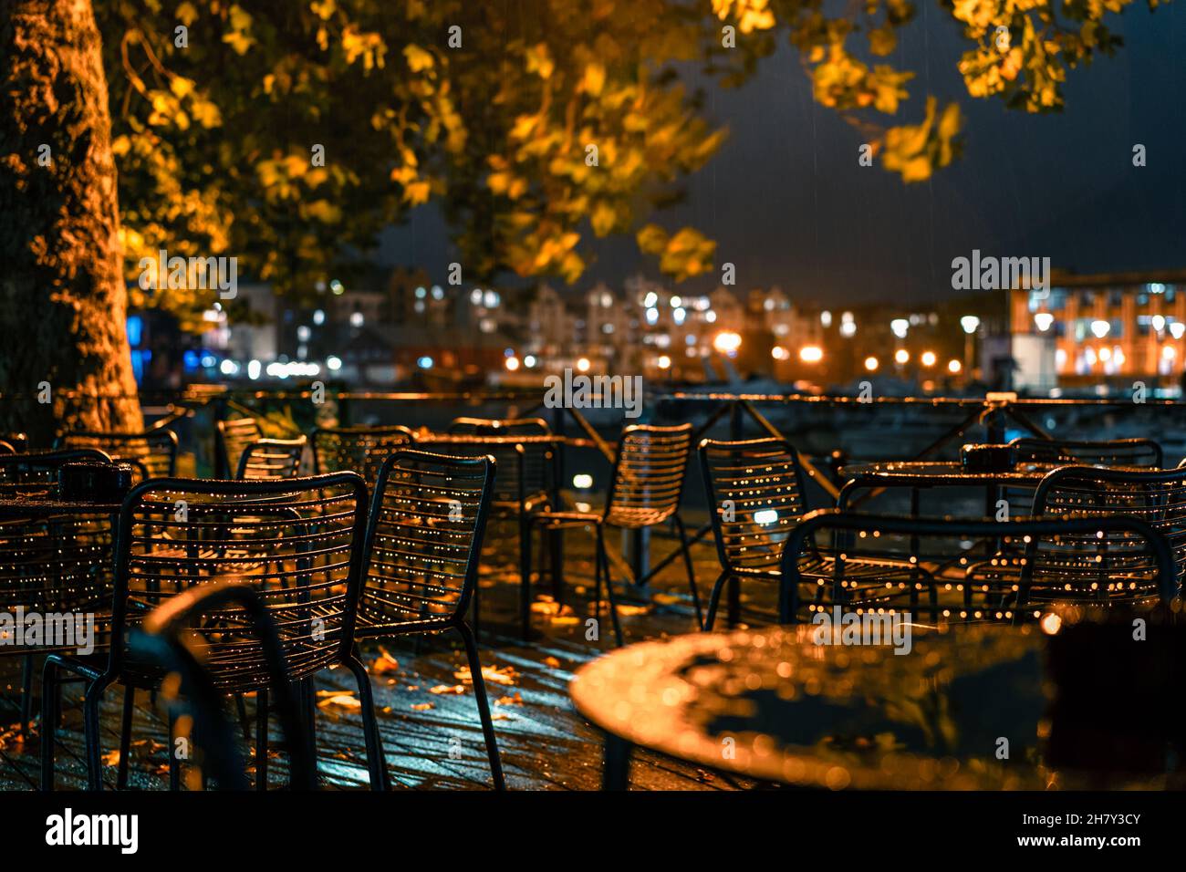 City cafe terrace near the river in the rainy autumn evening in the ...