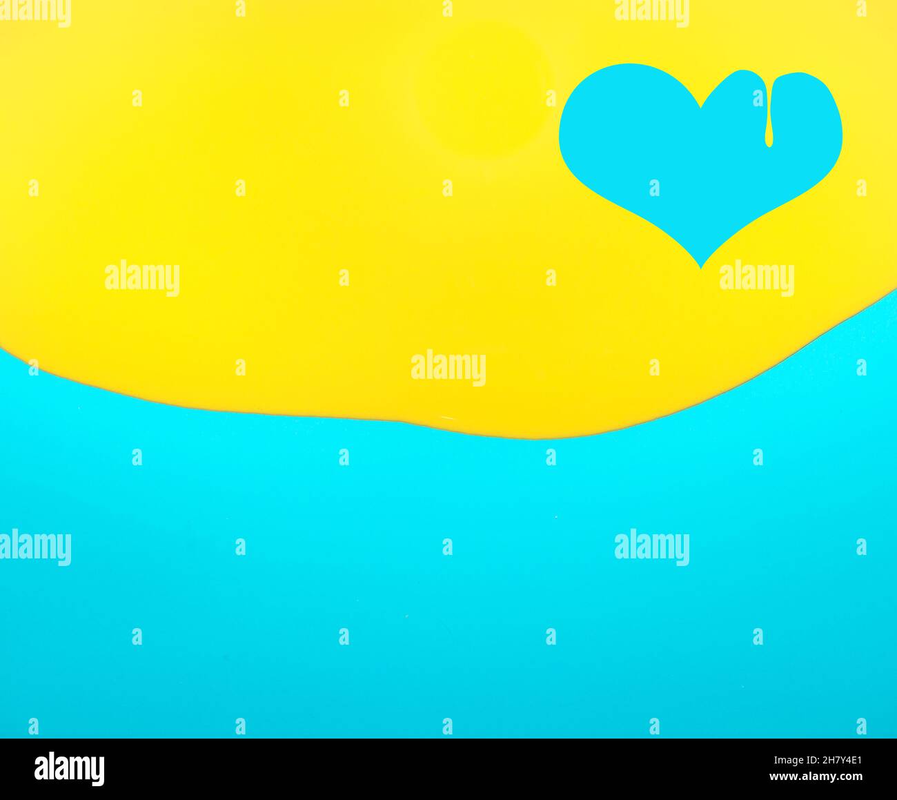 Heart shaped symbol made of dripping yellow paint on blue background ...