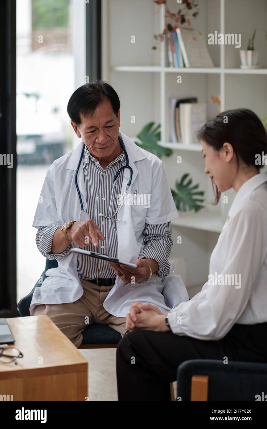 Senior asian doctor physician consulting young female patient, talking ...